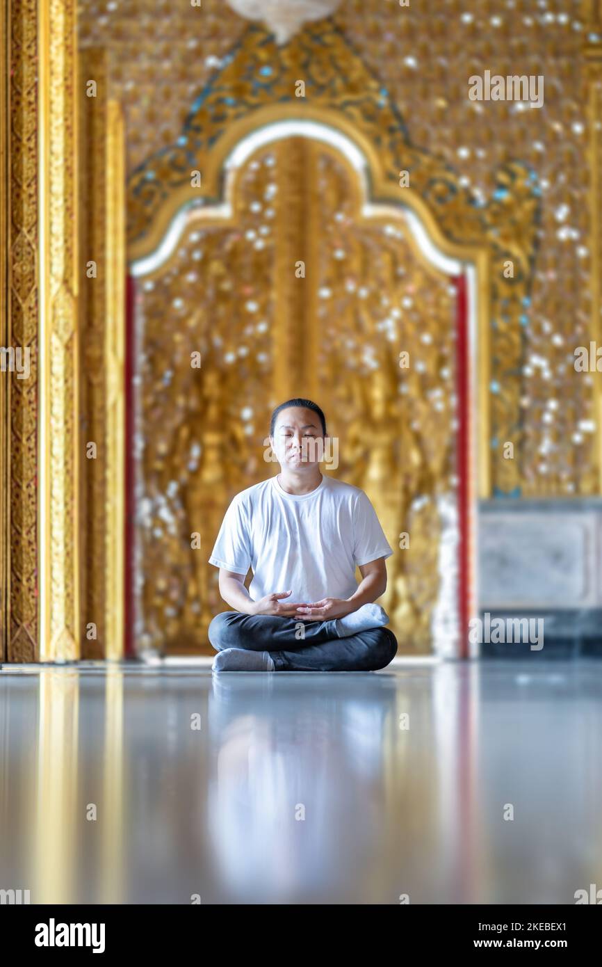 Asian Man meditates on the ground with reflection in the sunlight ...