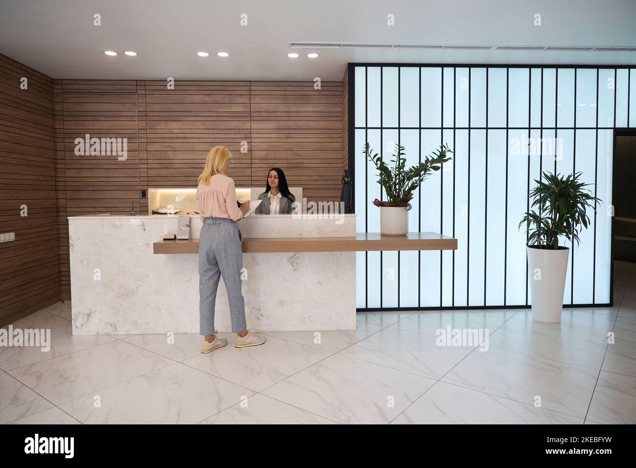 Client filling up form at reception desk Stock Photo - Alamy