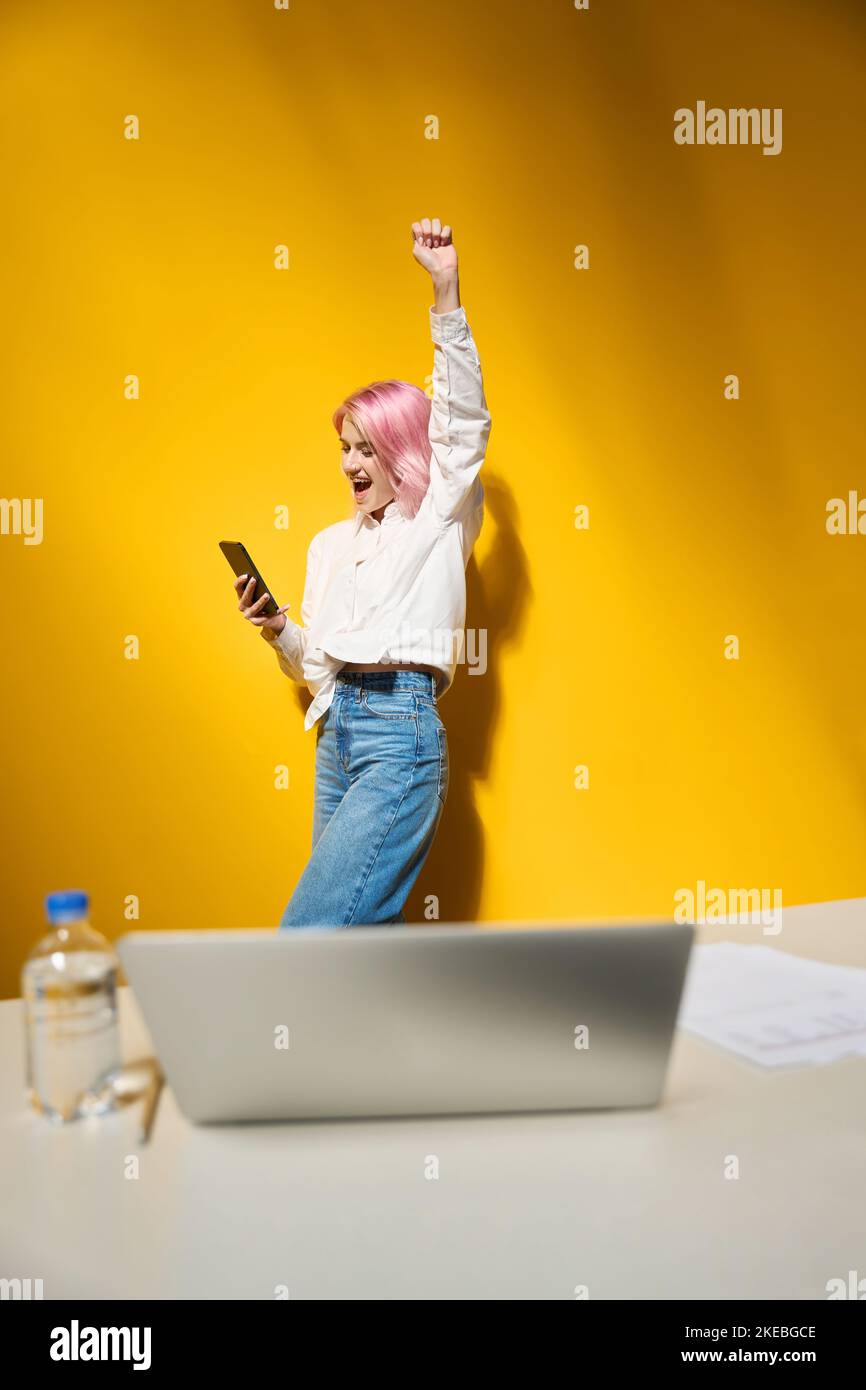 Happy female standing on yellow background and rejoice Stock Photo - Alamy