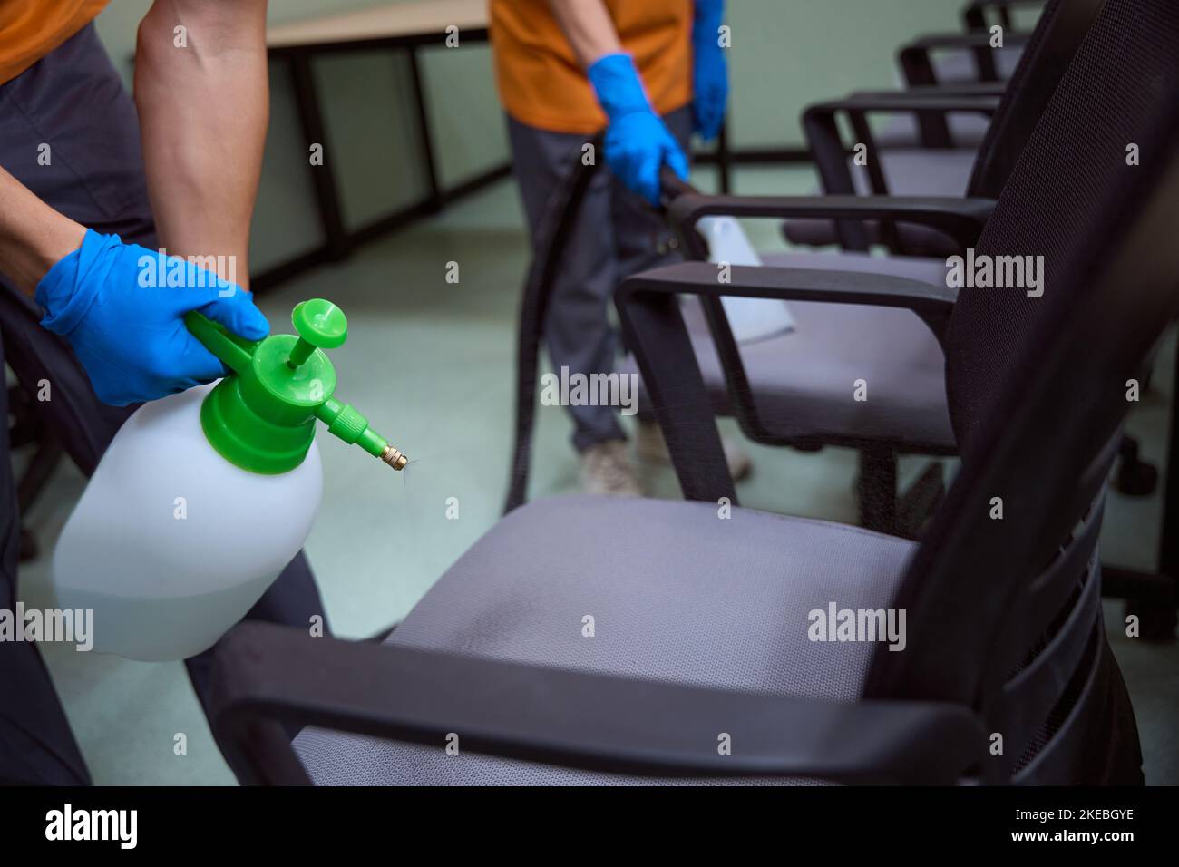 Well-trained cleaners spraying sanitizer and removing dust from chairs ...