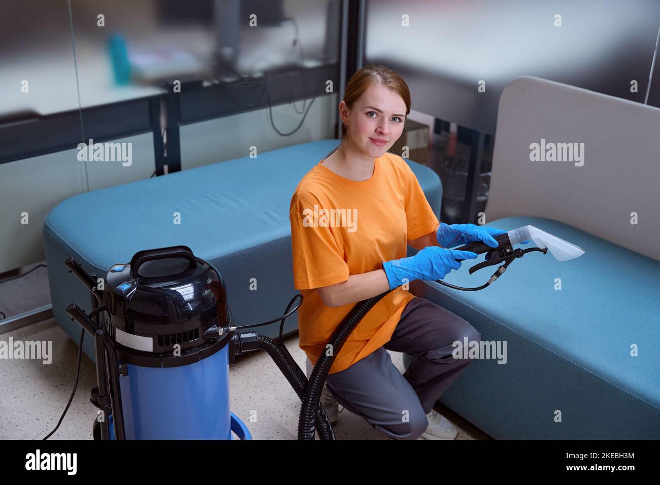 Cleaning service employee posing with cleaning equipment near furniture ...