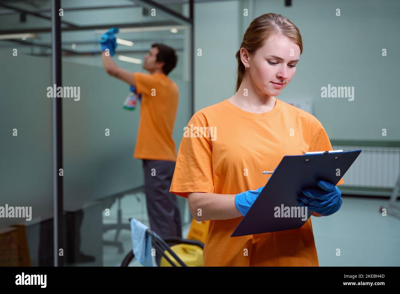 Cleaning copany employee following a checklist with her partner working ...