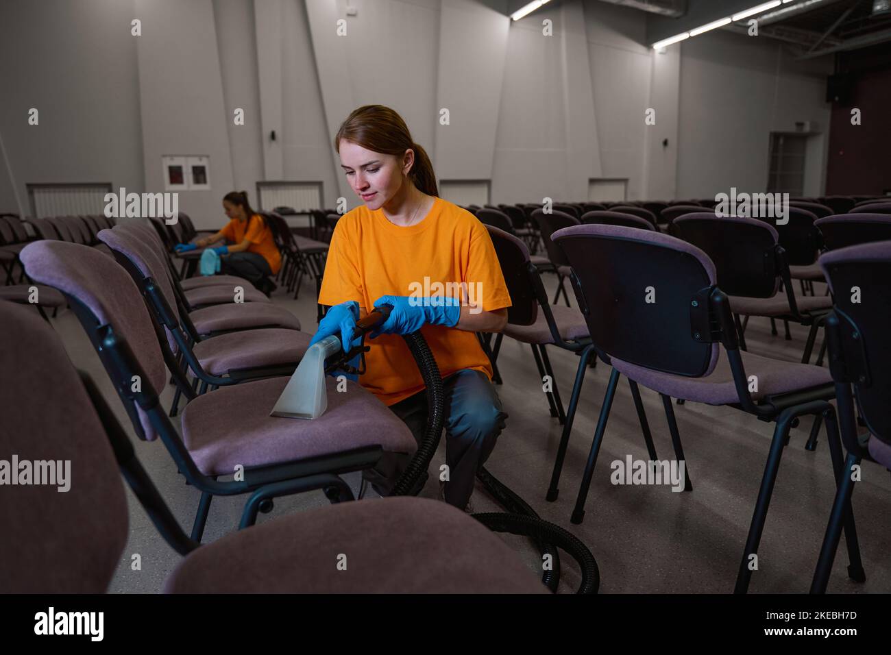 Two cleaning company workers sanitizing the chairs in sitting area ...