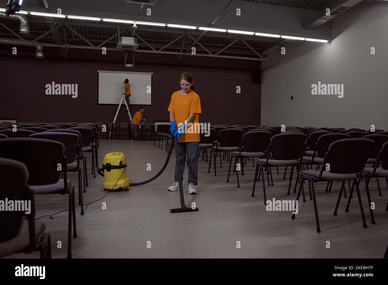 Team of professional cleaners doing big cleanup in presentation hall ...