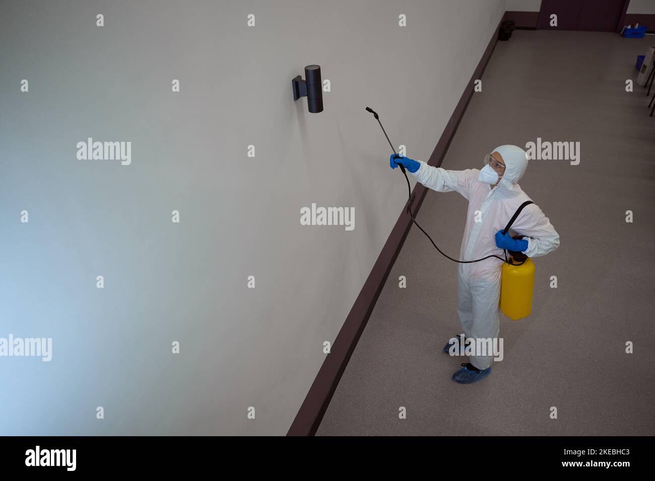 Professional janitor sanitizing walls while wearing protective gear ...