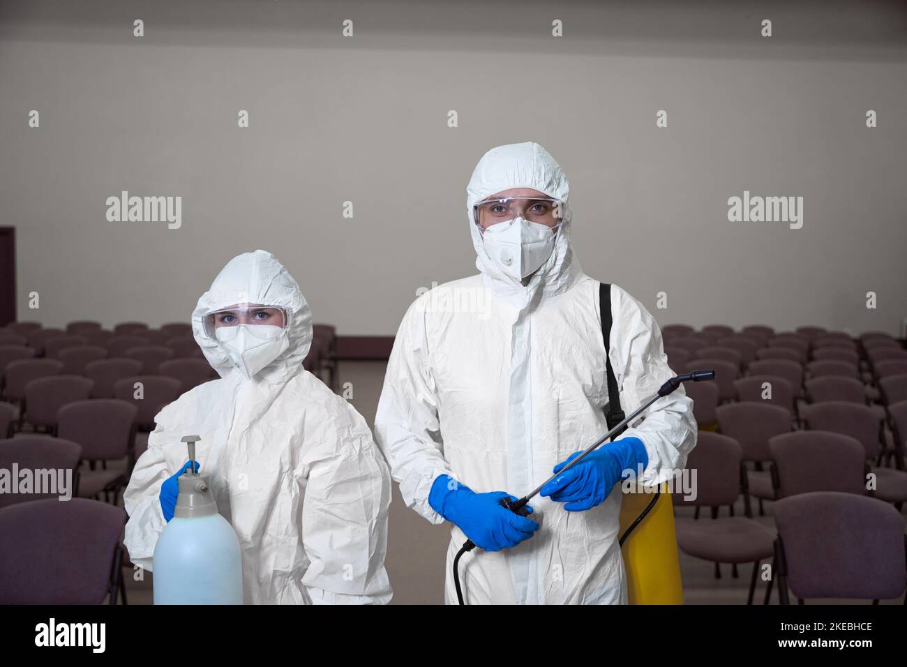 Skilled janitors in protection outfits and masks looking at camera ...