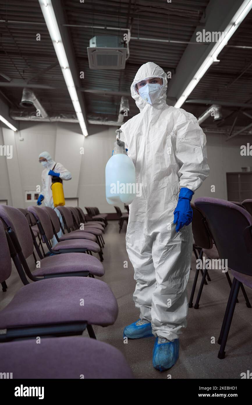 Cleaner wearing personal protective gear during disinfection of ...