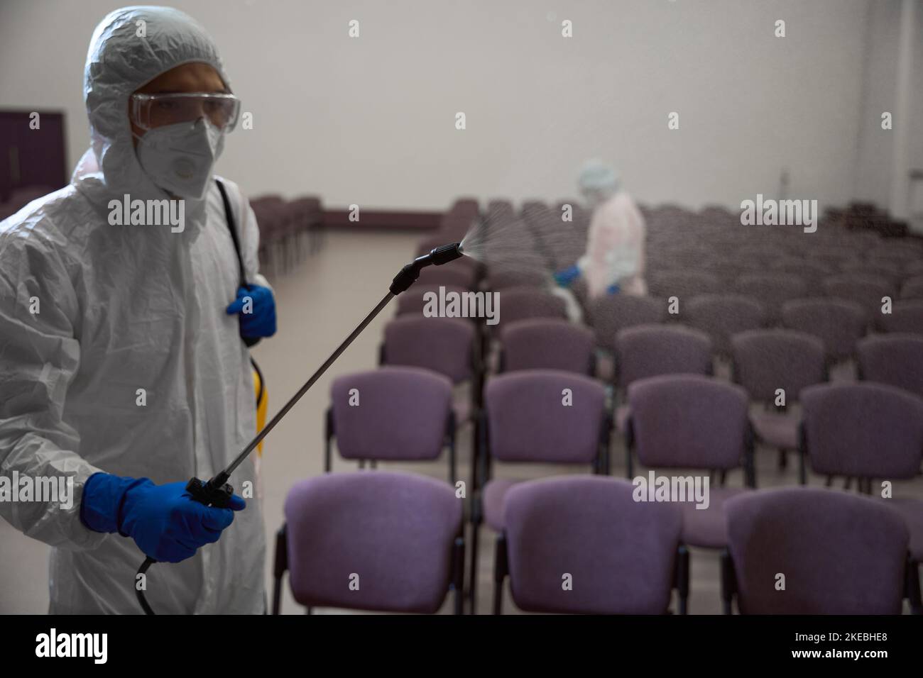 Professional janitors in immersion suits busy sanitizing chairs in ...