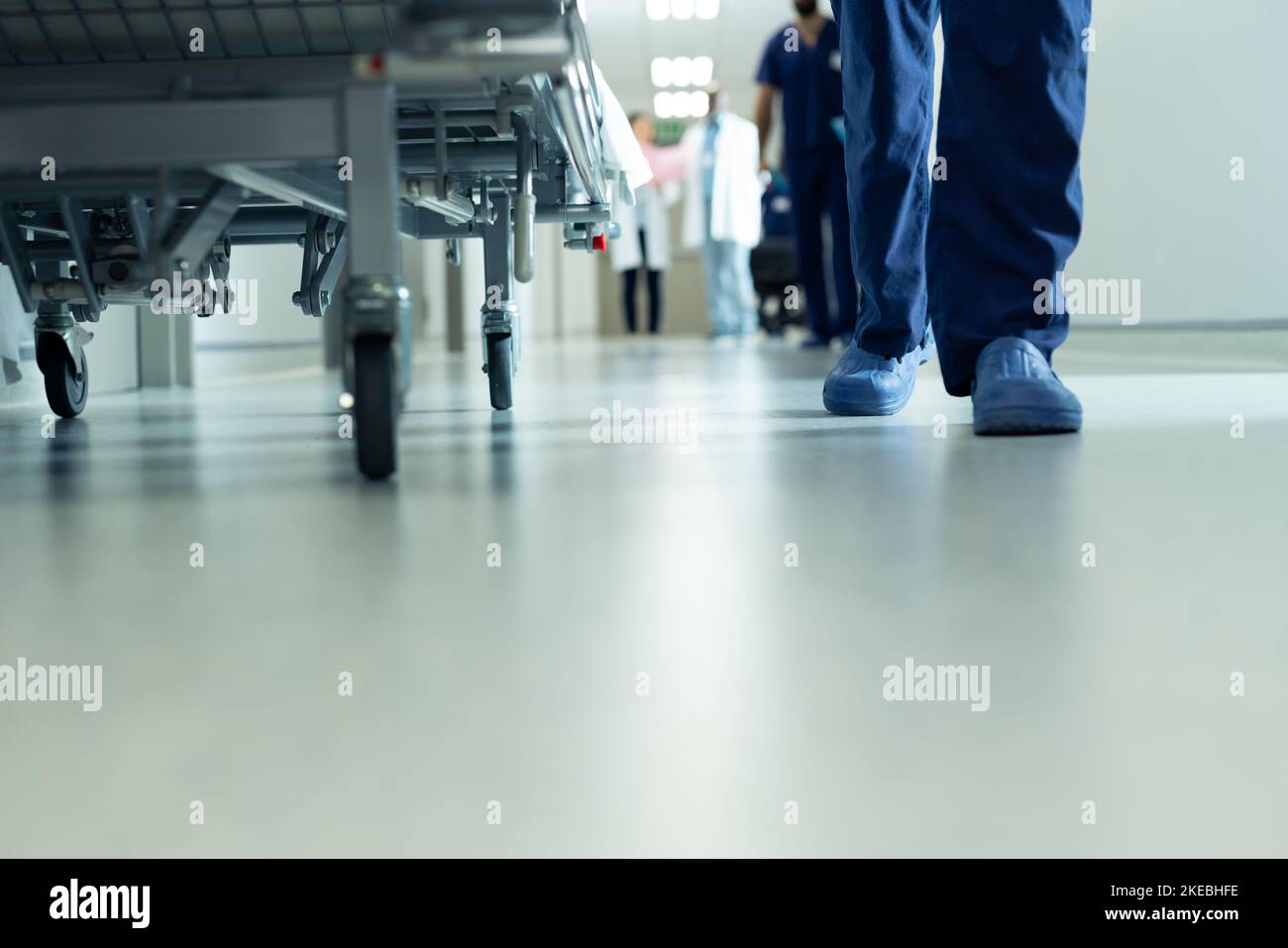 Low section of legs of hospital workers walking and hospital bed in ...
