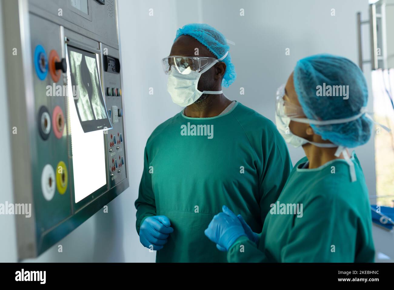 Two diverse surgeons discussing x-ray on lightbox in operating theatre ...