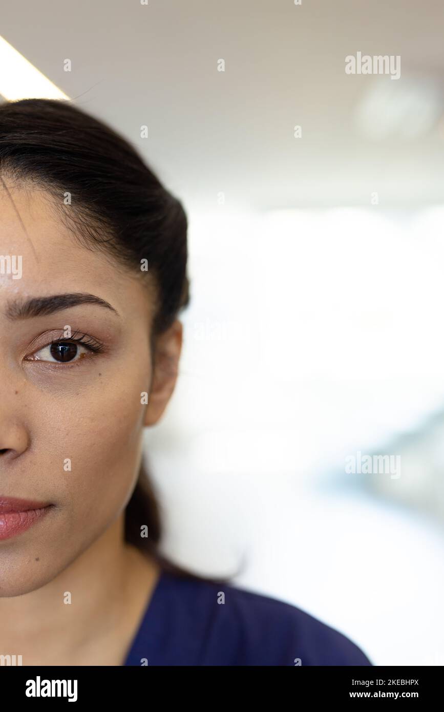 Vertical half face portrait of biracial female healthcare worker, with ...