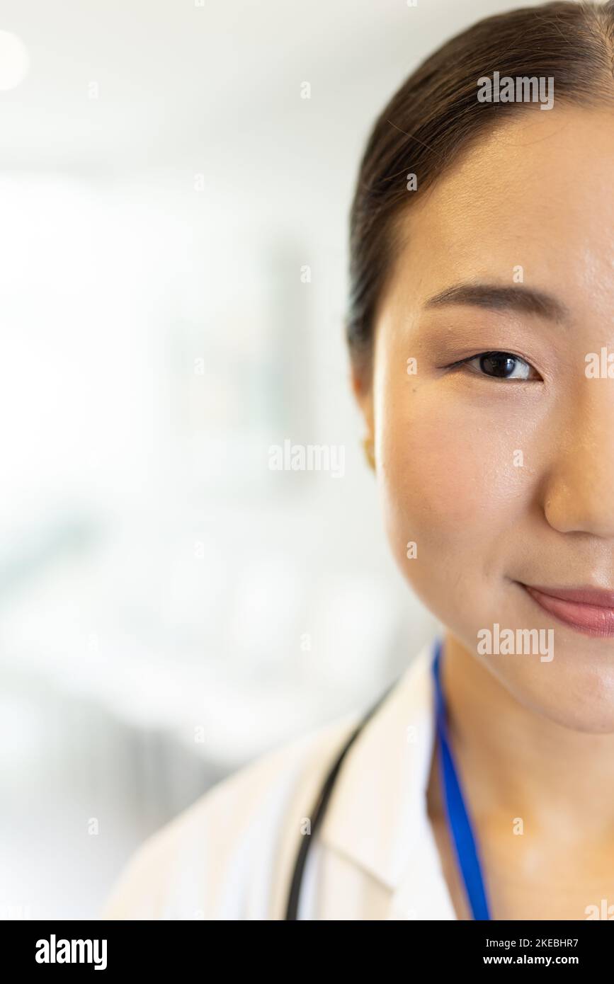 Vertical half face portrait of smiling asian female doctor in hospital ...