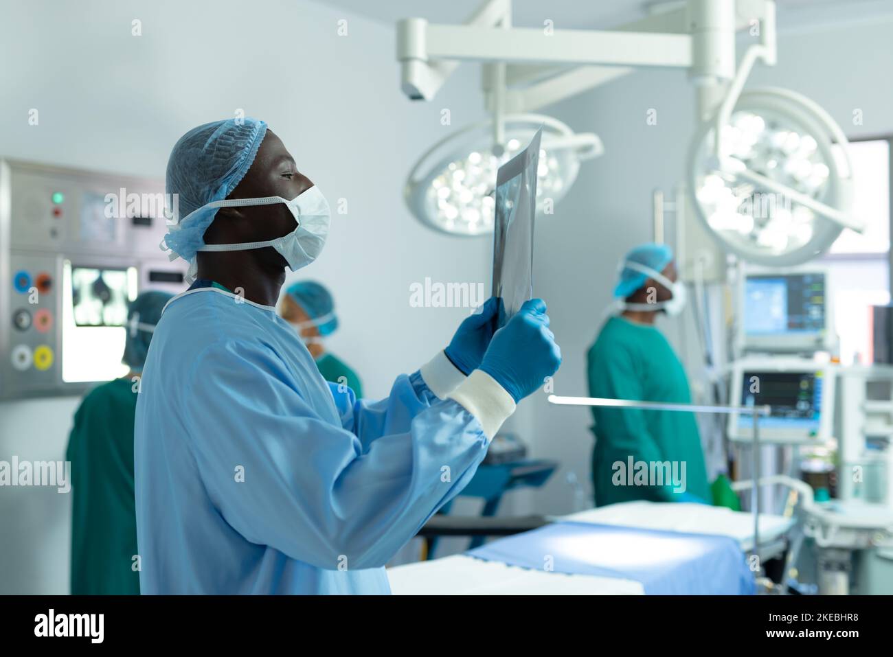 African american male surgeon studying x-ray in operating theatre, with ...