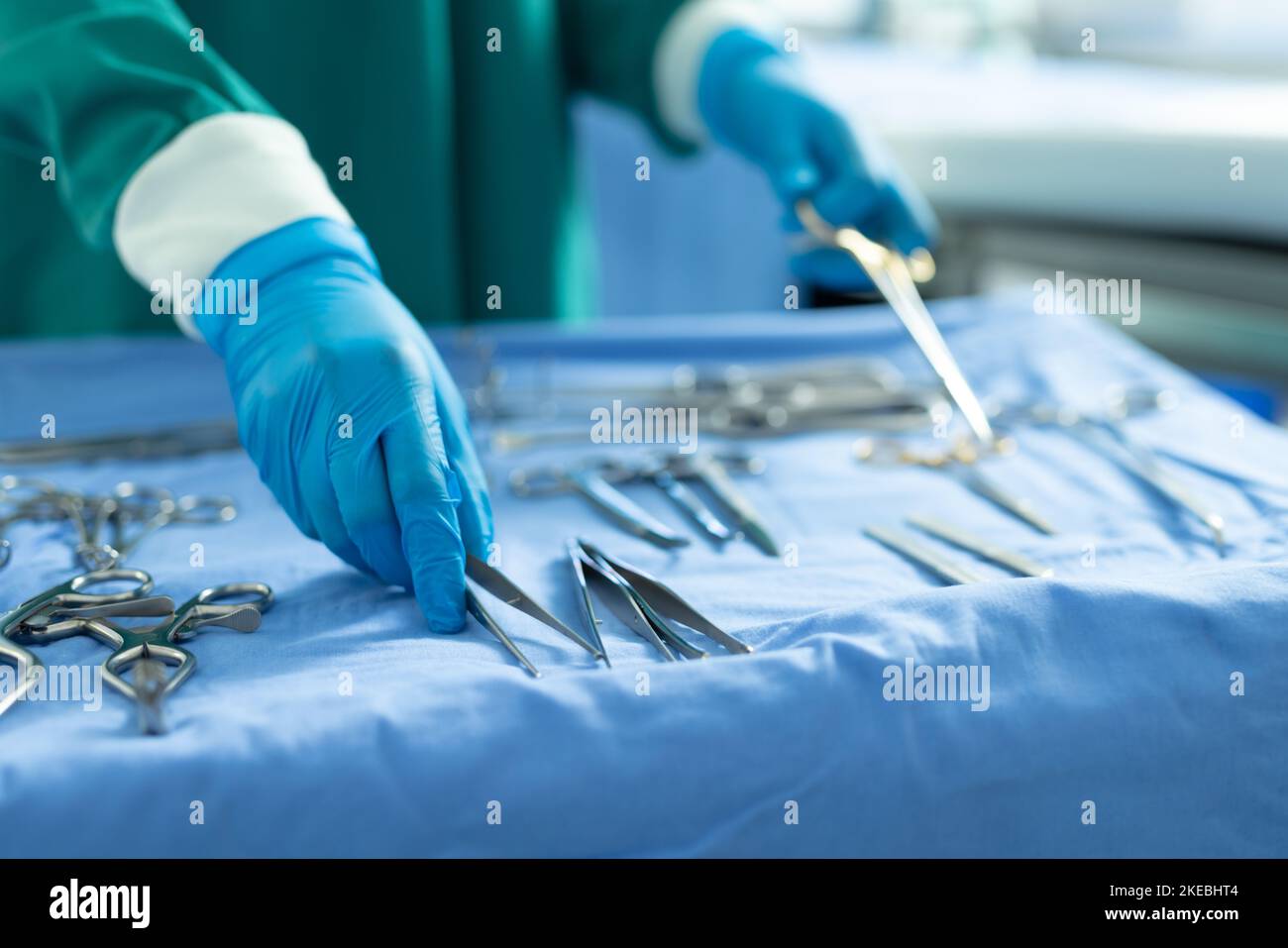 Midsection of surgical tech placing surgical tools on table in ...