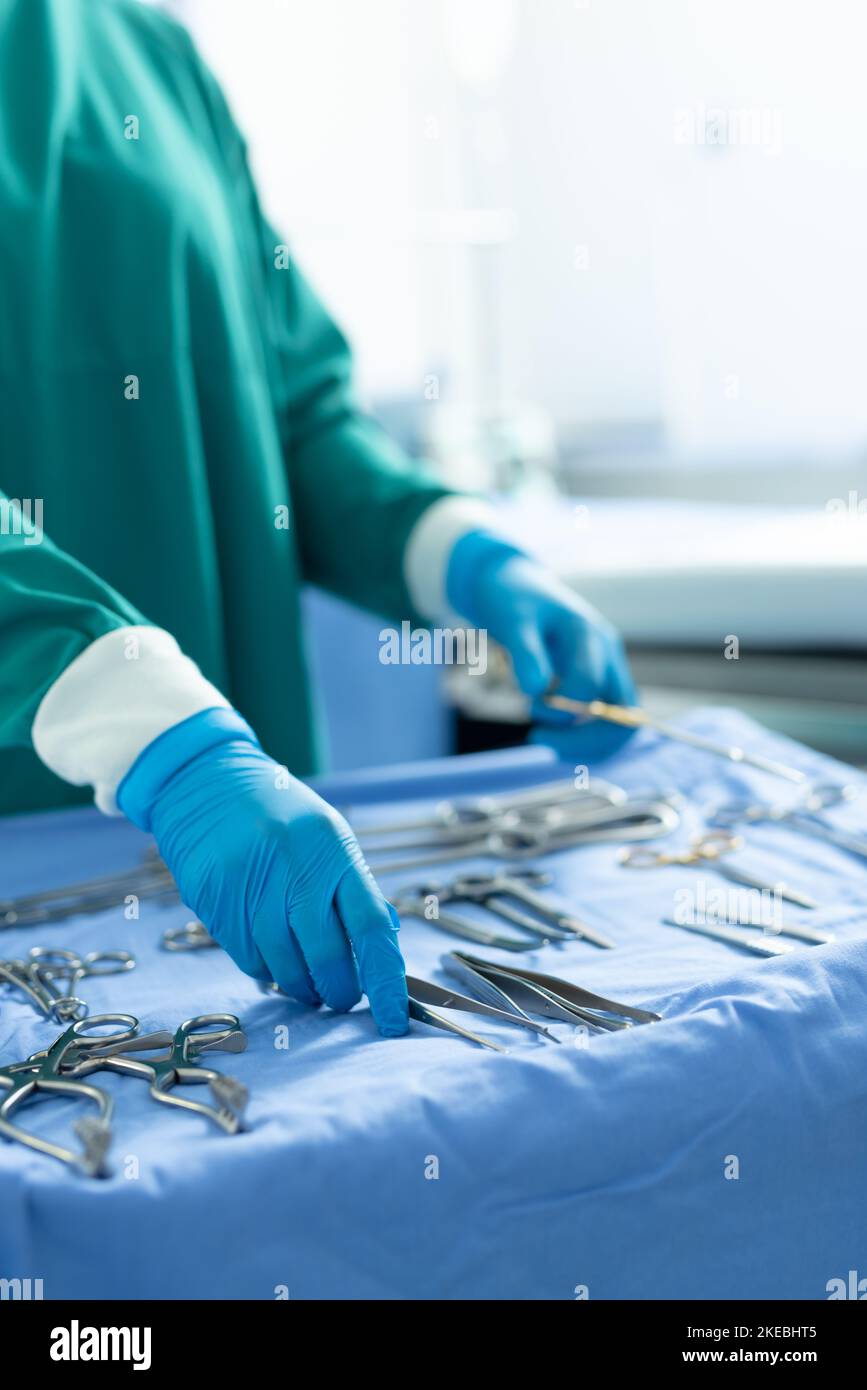 Vertical of midsection of surgical tech placing tools on table in ...