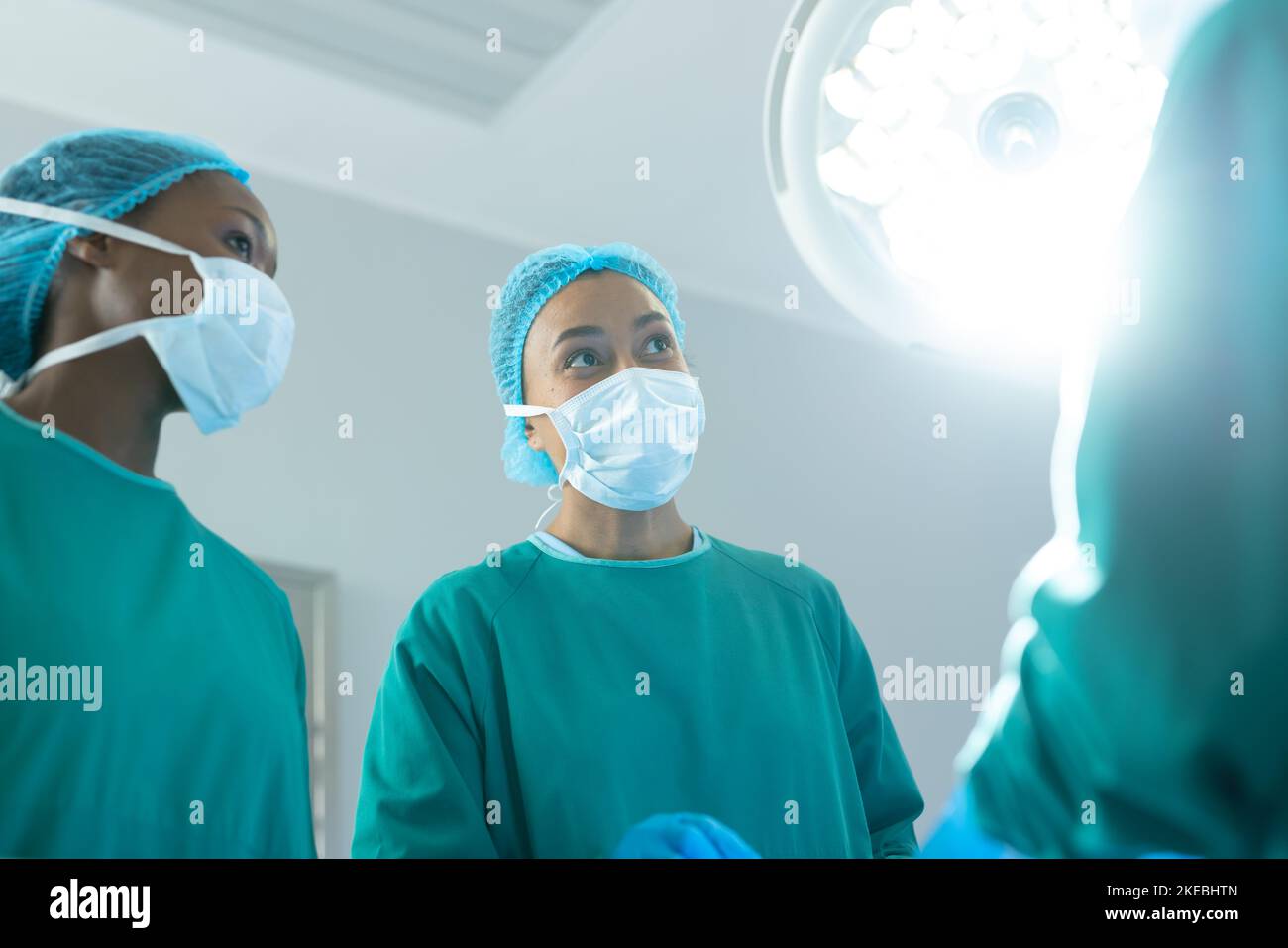 Two diverse female surgeons talking with colleague in theatre during ...