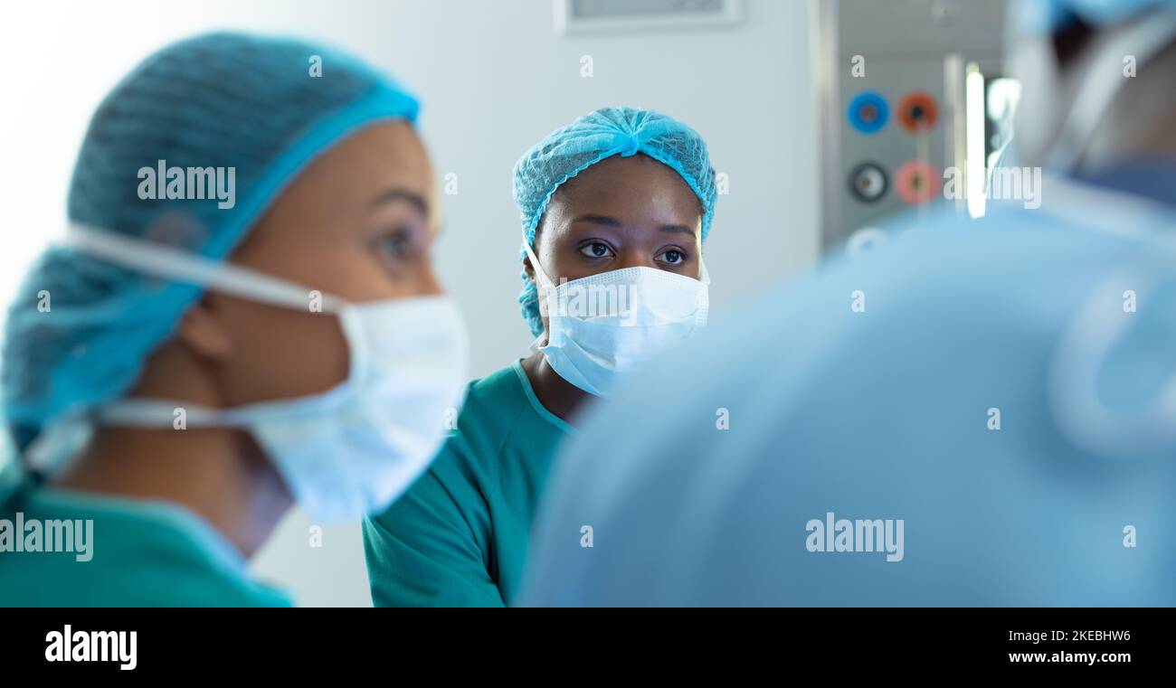 Two diverse female surgeons talking with colleague in theatre during ...