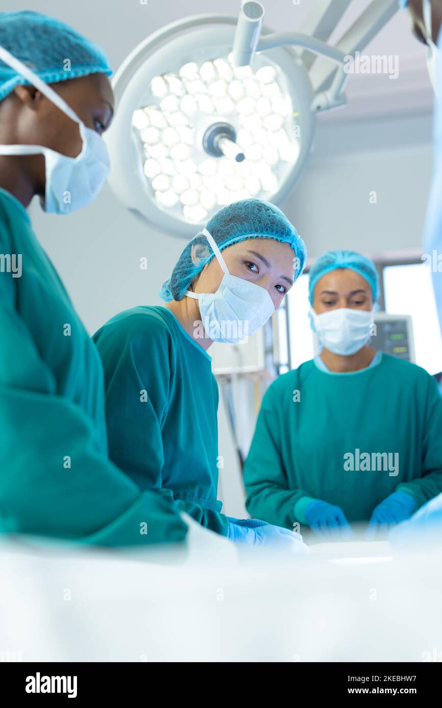 Vertical of three diverse female surgeons in theatre during operation ...