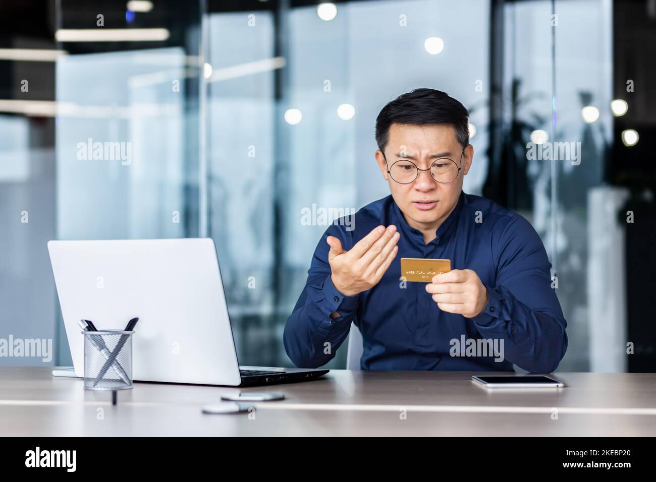 Upset and sad asian businessman inside office, man holding smartphone ...