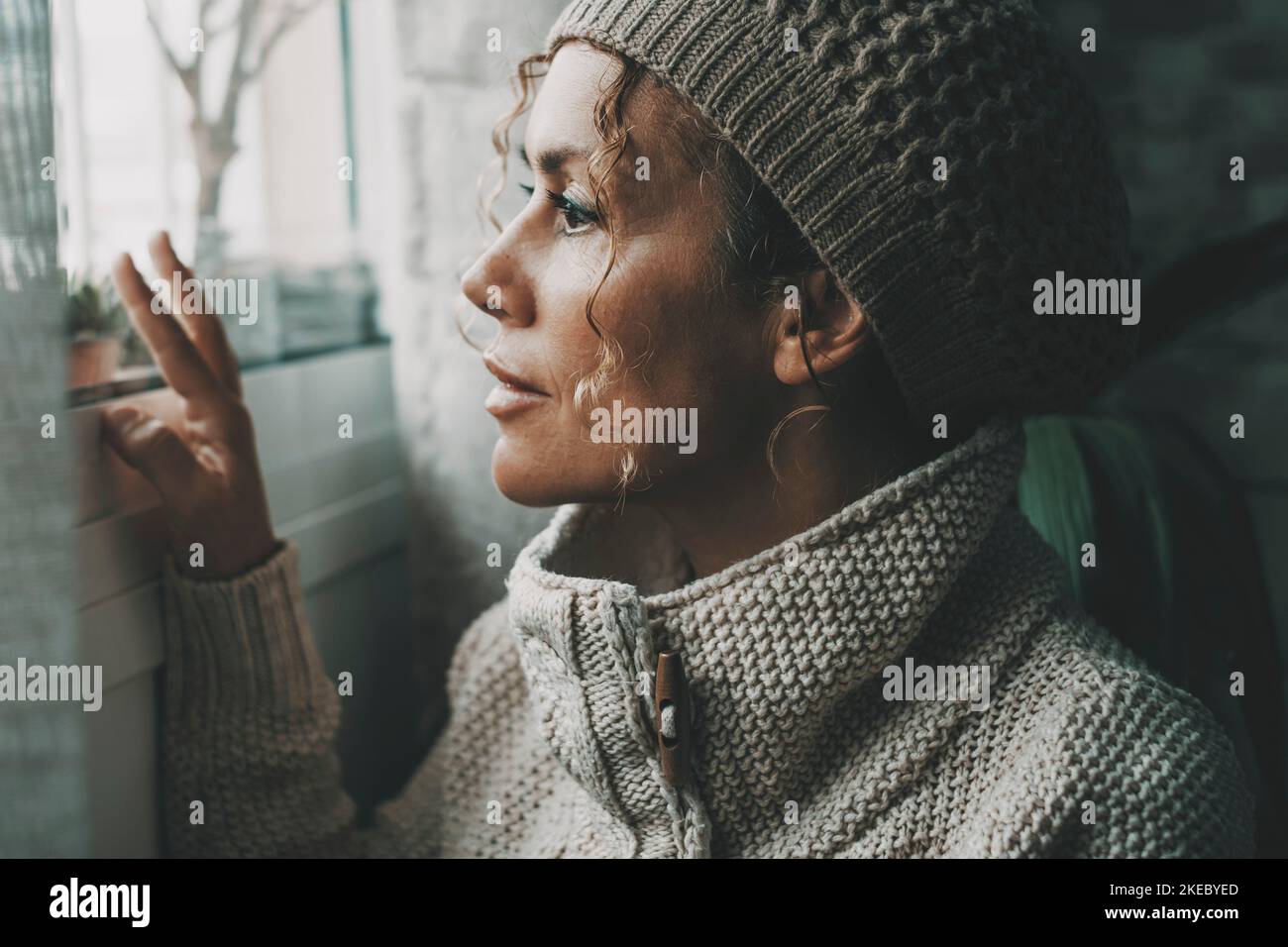 Side portrait close up of young mature woman looking outside the window ...