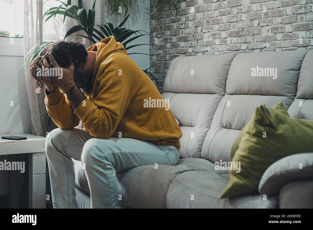 One man alone at home holding his head with desperation and frustration ...