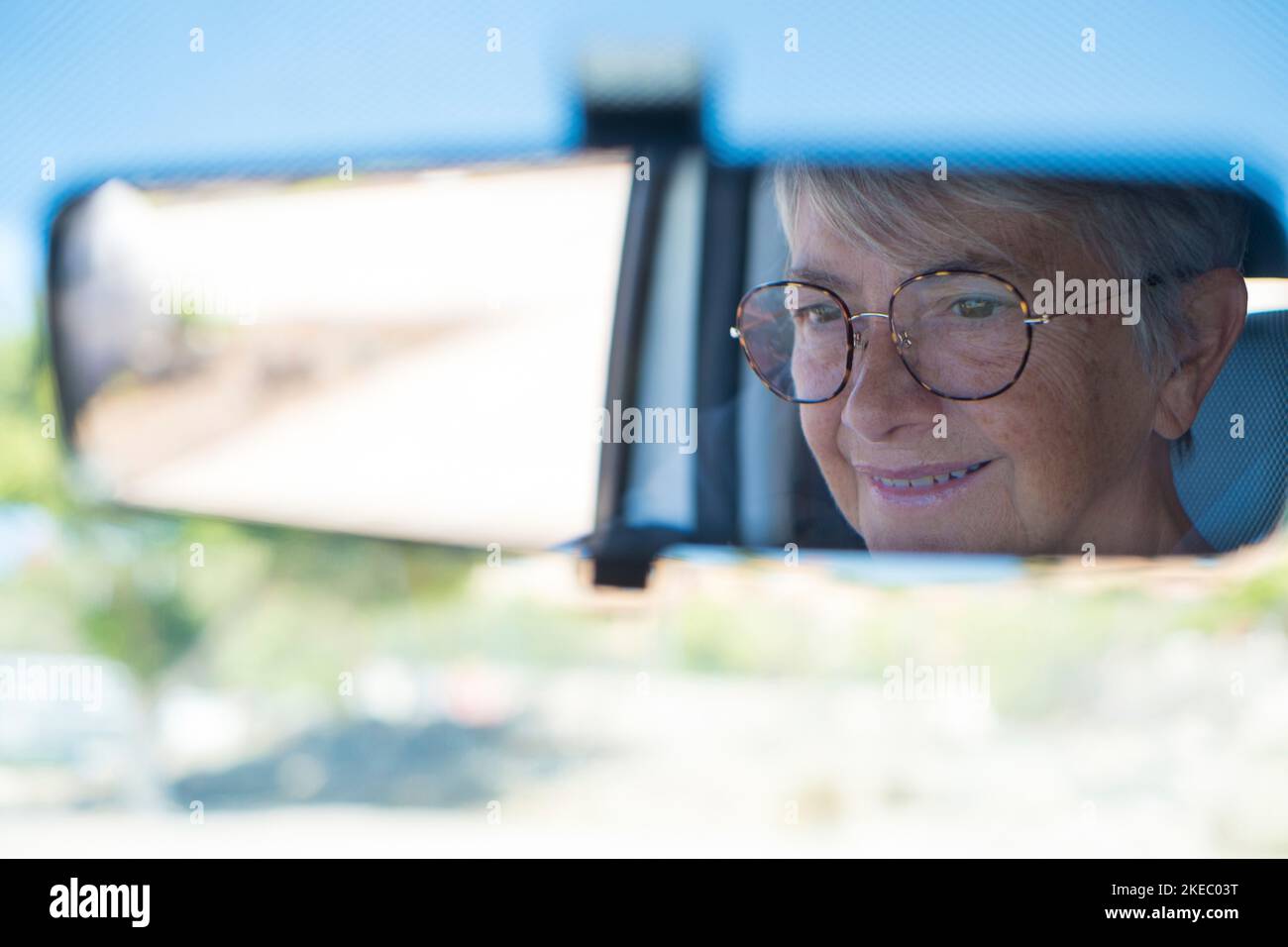 Close up of one old woman looking at the road while driving. Back ...