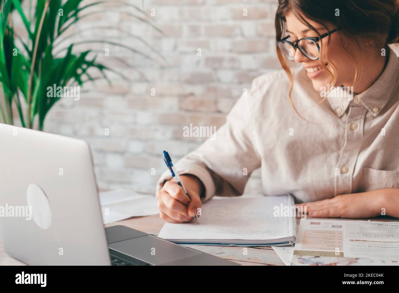 Smiling woman write notes watch webinar study work on laptop, young ...