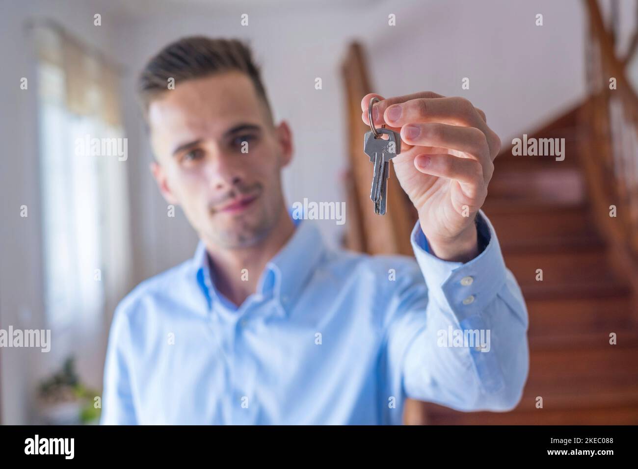 Portait of young man showing keys of house. Young man holding keys of ...
