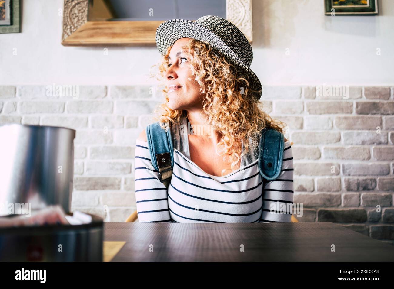 portrait of beautiful curly woman at the table of restaurant thinking ...