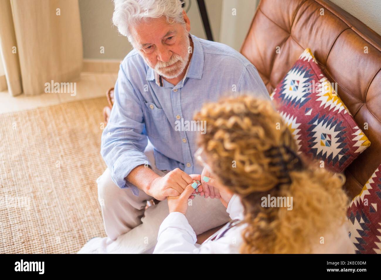 Young female doctor checking and helping senior man at his home. Doctor ...