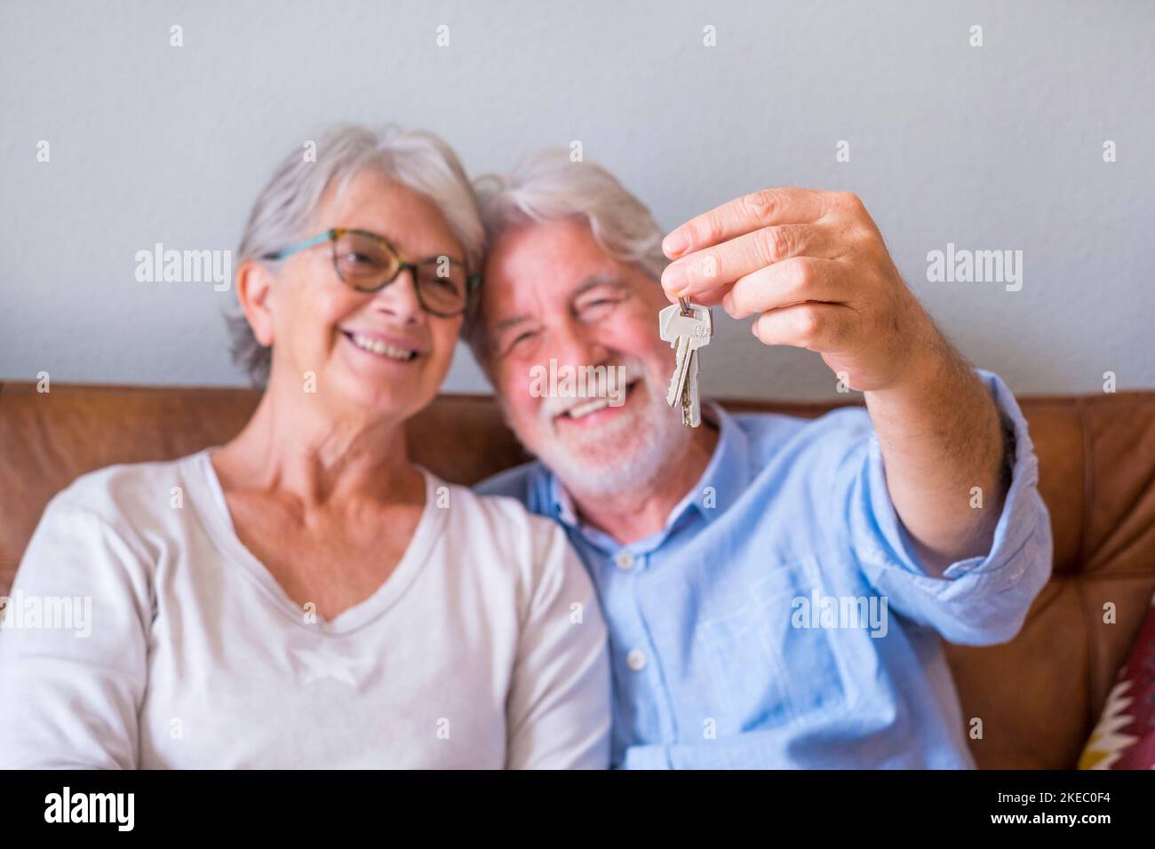 Close up of senior couple showing keys of house. Elderly couple holding ...