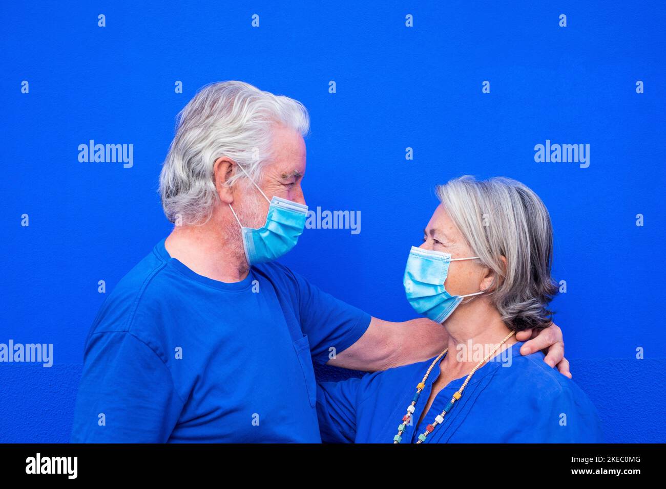 couple of two happy senior smiling under the mask on their face ...