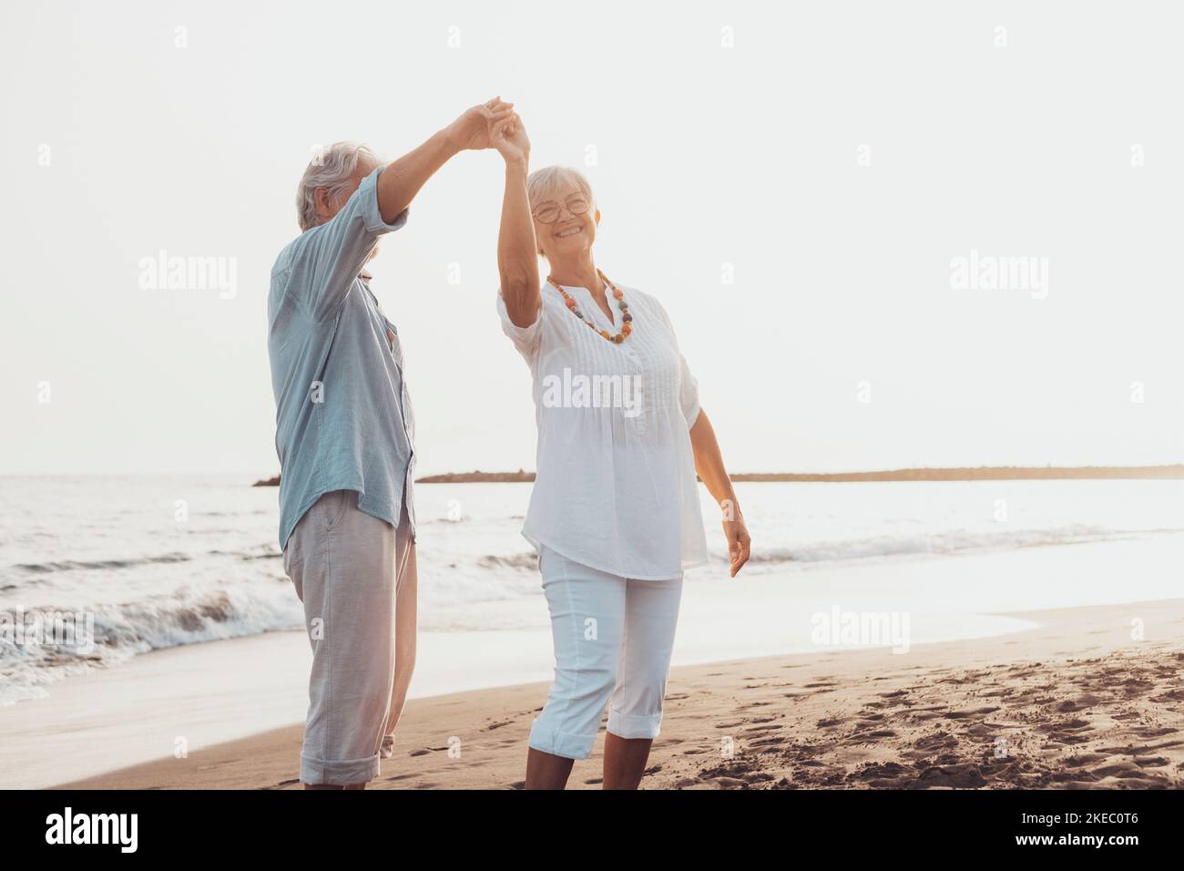 Couple of old mature people dancing together and having fun on the sand ...