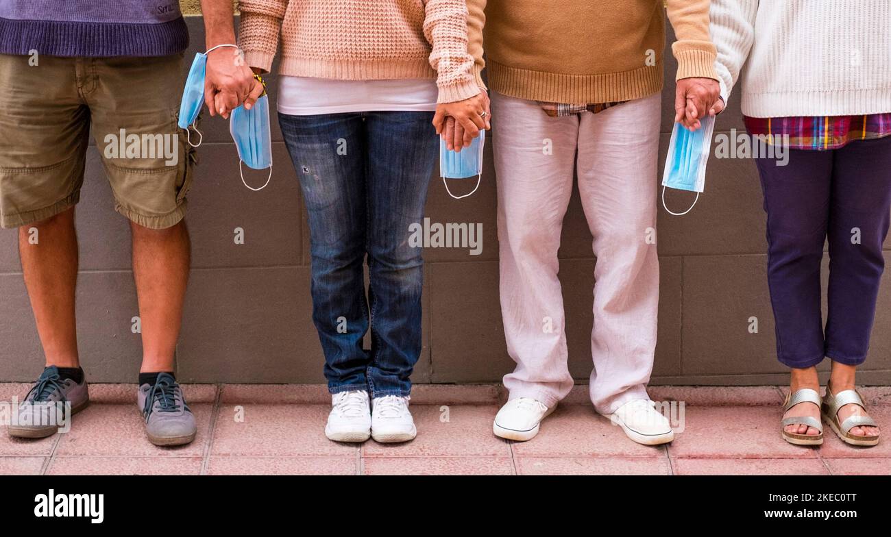 close up of legs and body of four people holding their hands together ...