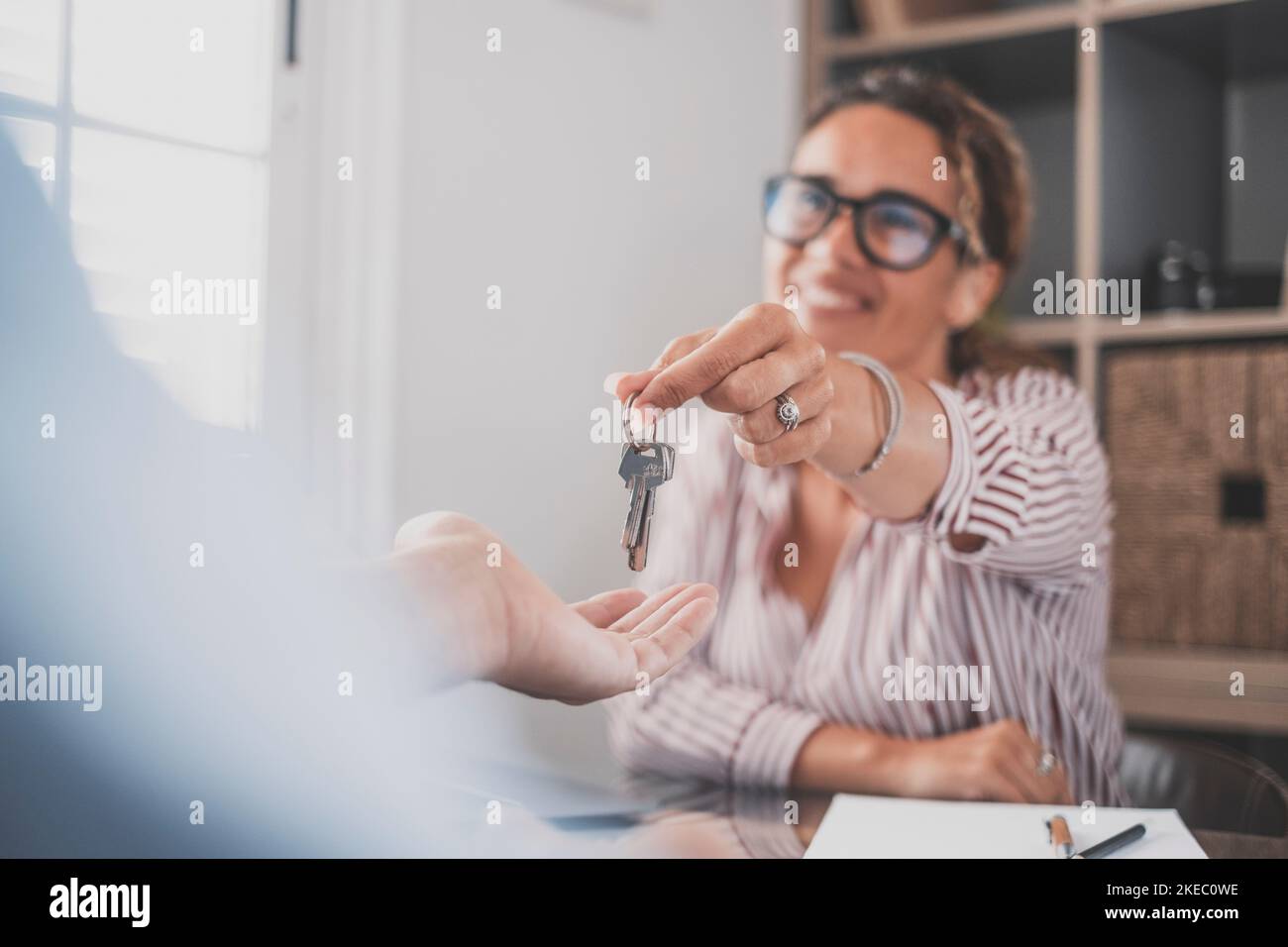 Smiling female realtor agent giving keys to apartment buyer. Homeowner ...