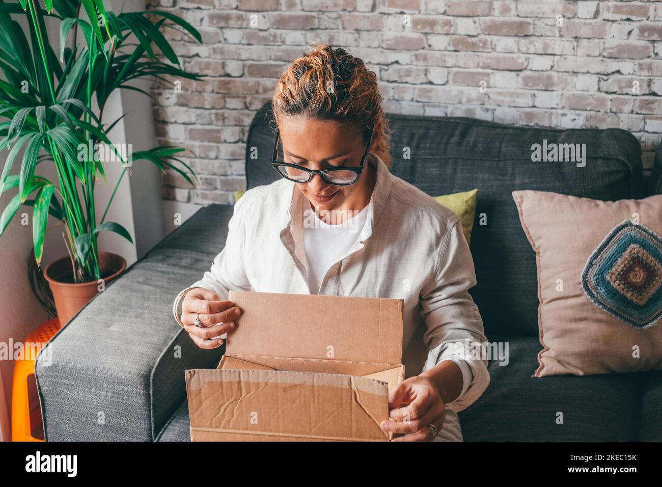 Woman unpacking delivdery box opening package at home. Happy young lady ...