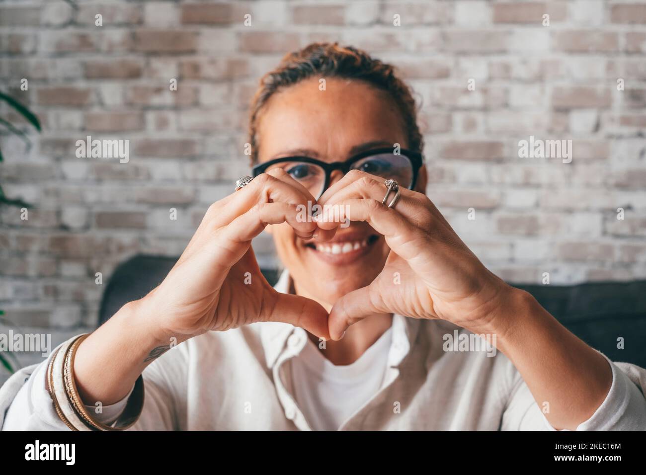 Happy young romantic woman looking at camera through heart shape made ...