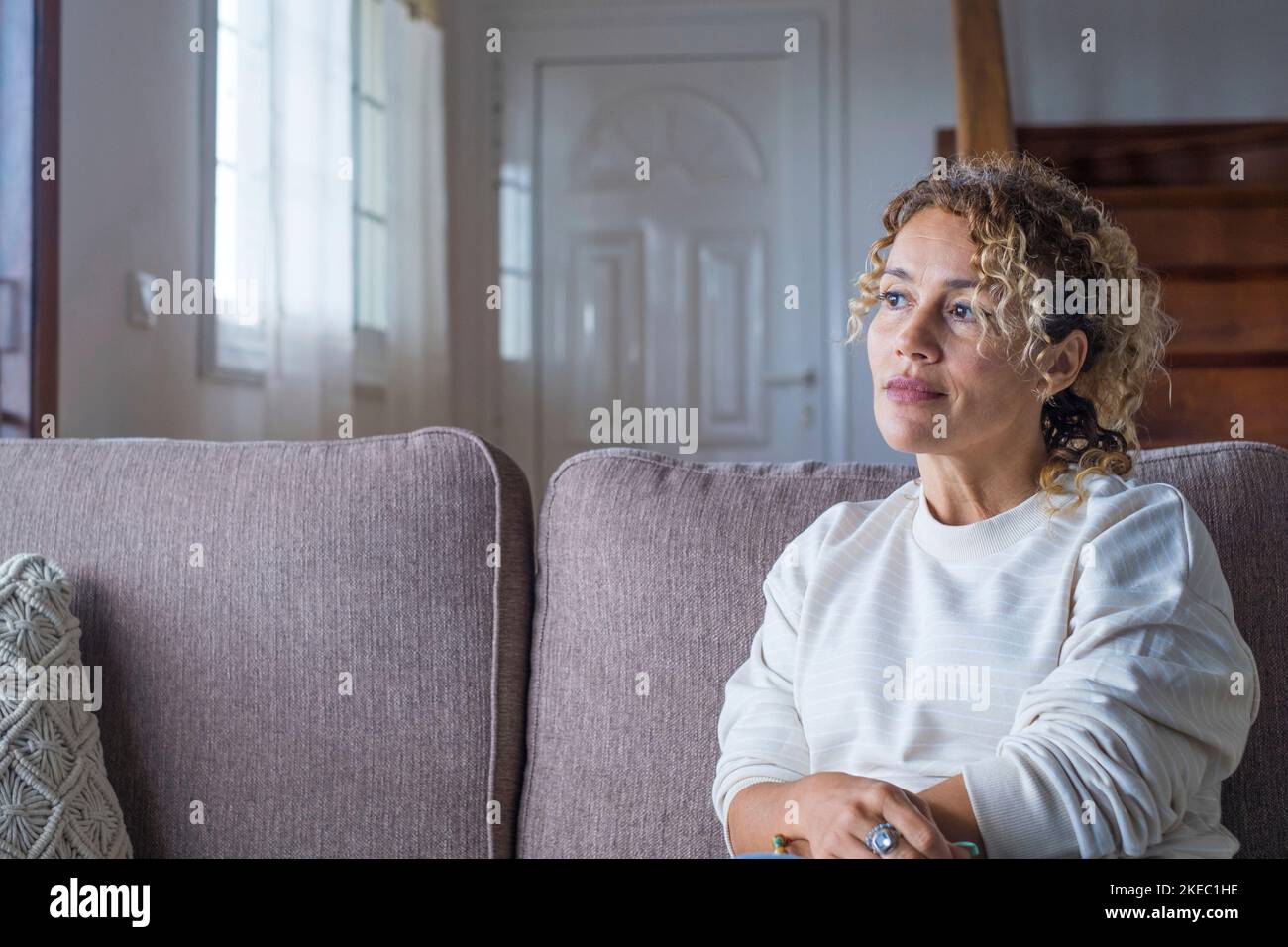 Thoughtful pensive girl sitting alone looking through window thinking ...
