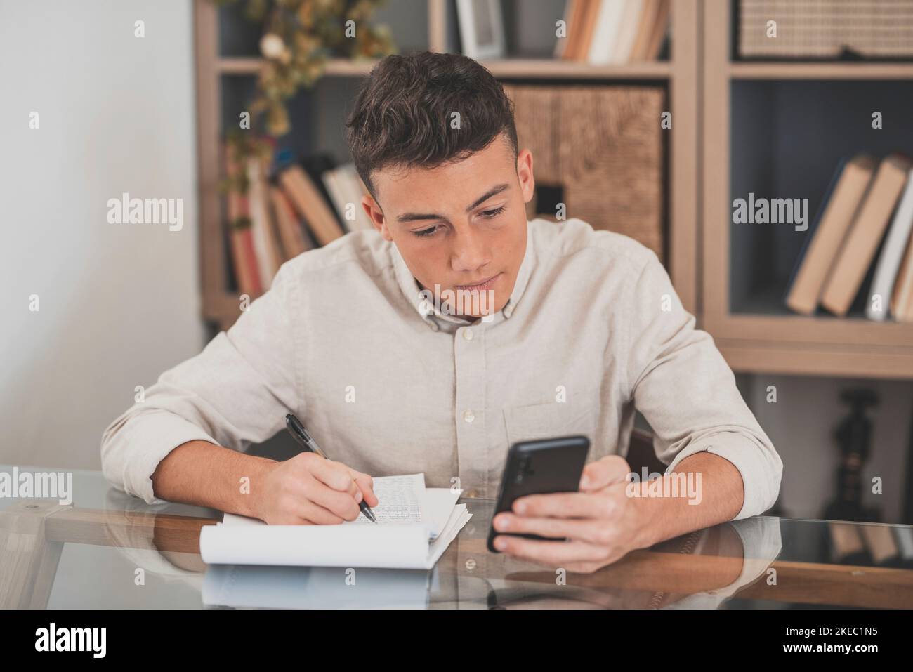 Happy young man using his smartphone at home surfing the net doing ...