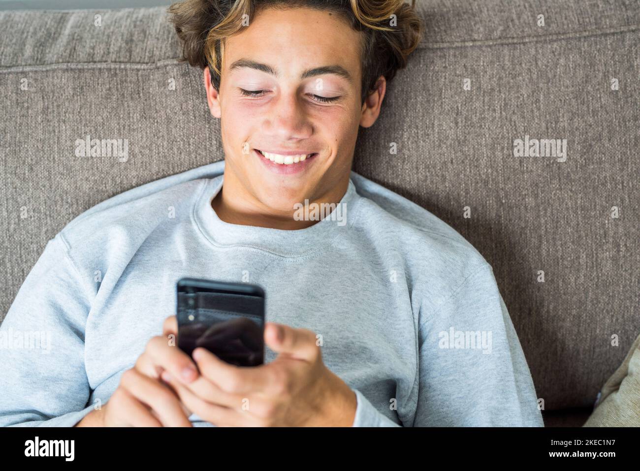 portrait and close up of man teenager smiling and using his phone on ...