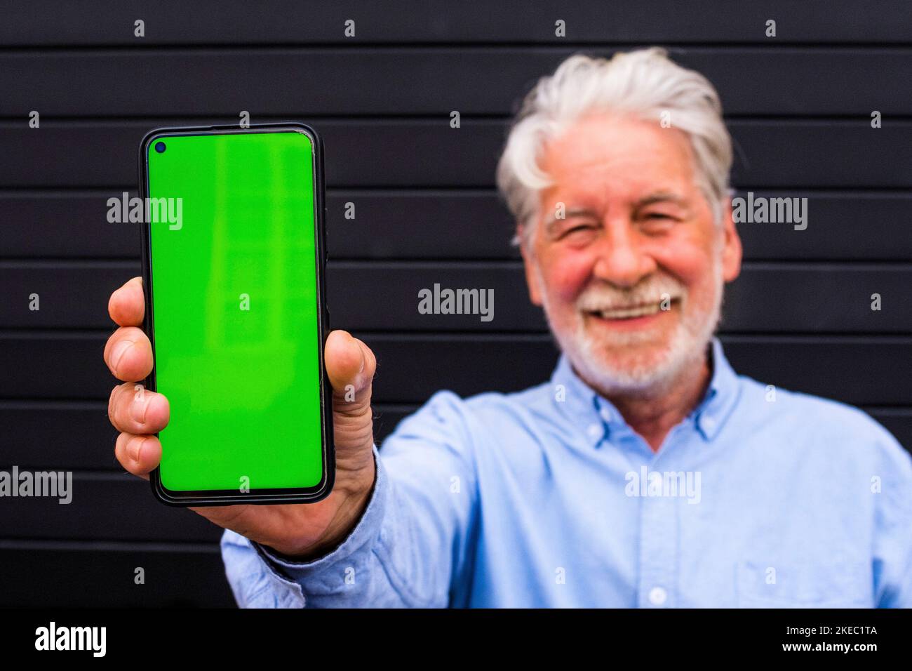 one old and mature senior man holding a mobile phone with green screen ...