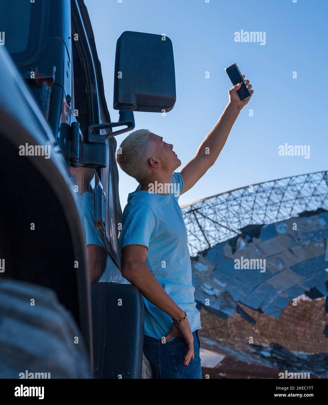 one young man or teenager looking for signal with his phone and car ...