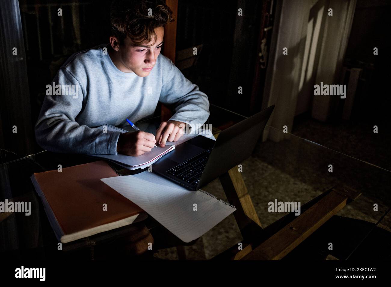 one teenager using his laptop at night doing homework in the online ...