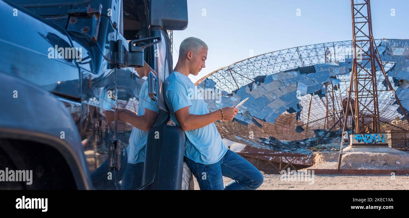 one young man holding and using a tablet or phone alone in the middle ...