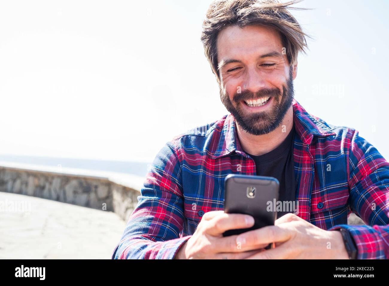 close up of attractive man holding and using a phone smiling and ...