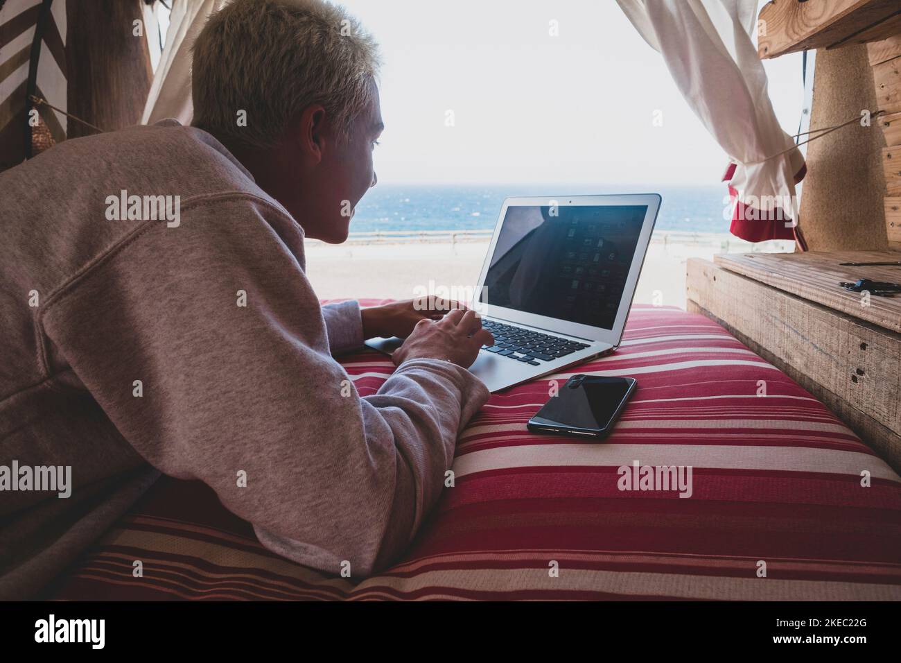 one happy man using a laptop inside a minivan in front of the sea ...