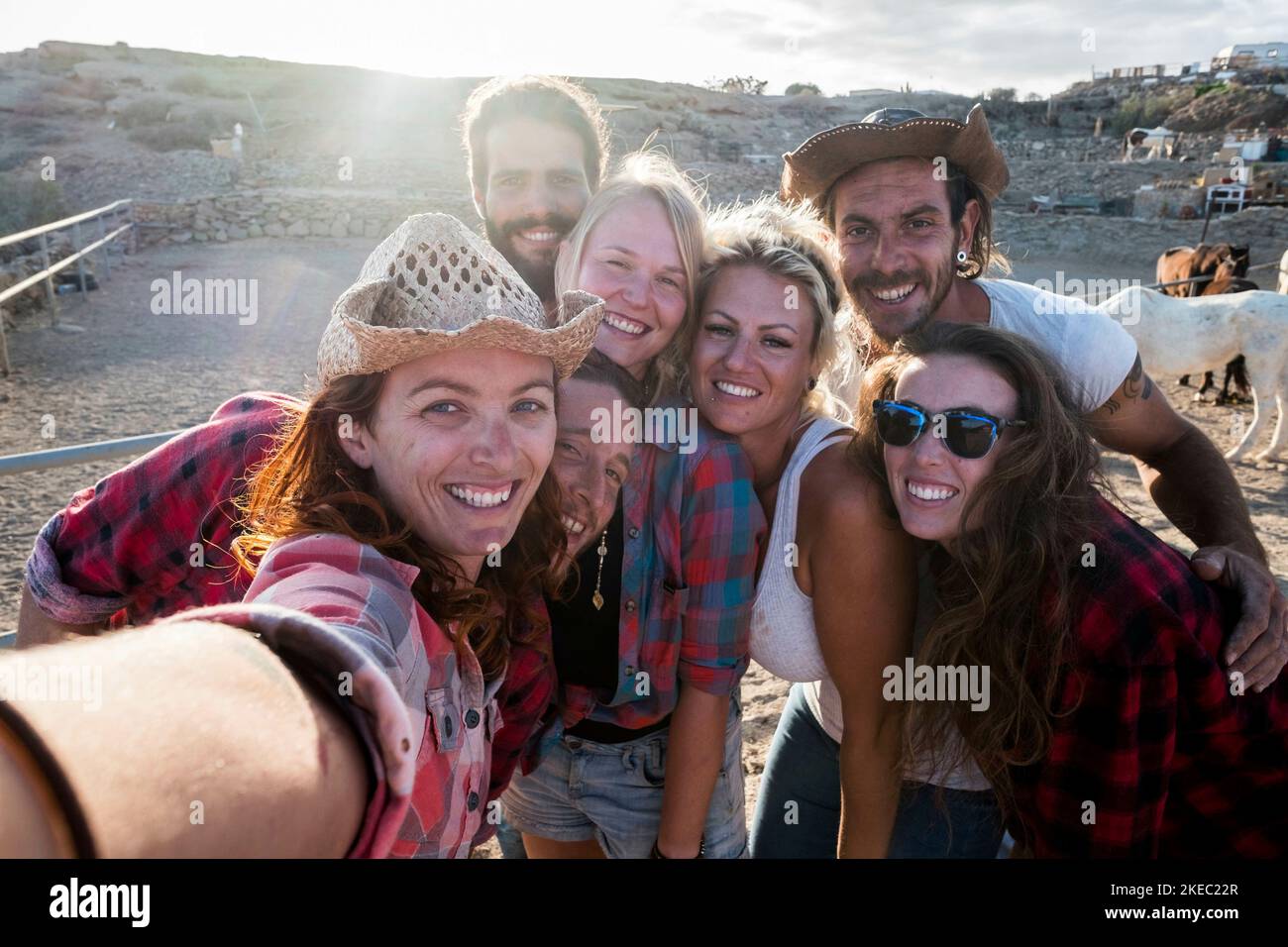 group of seven people together having fun in a ranch with horses ...