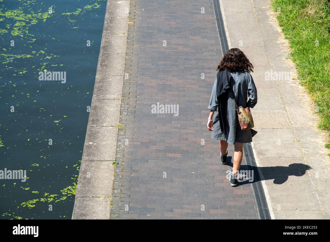 Woman walking alone on a pavement by riverbank. Healthy lifestyles ...
