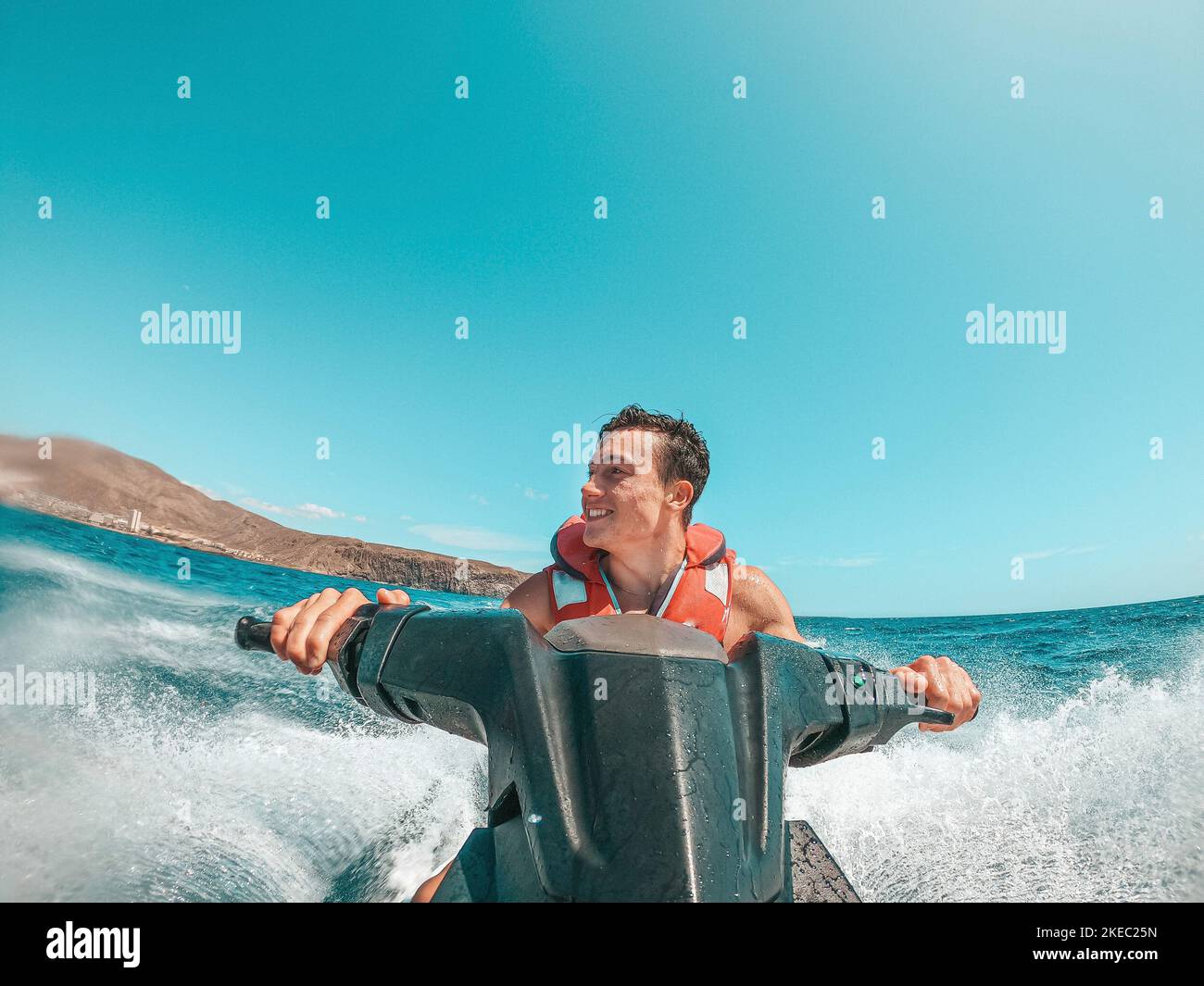 Teenager man enjoying summer in a jet ski in the middle of the sea ...