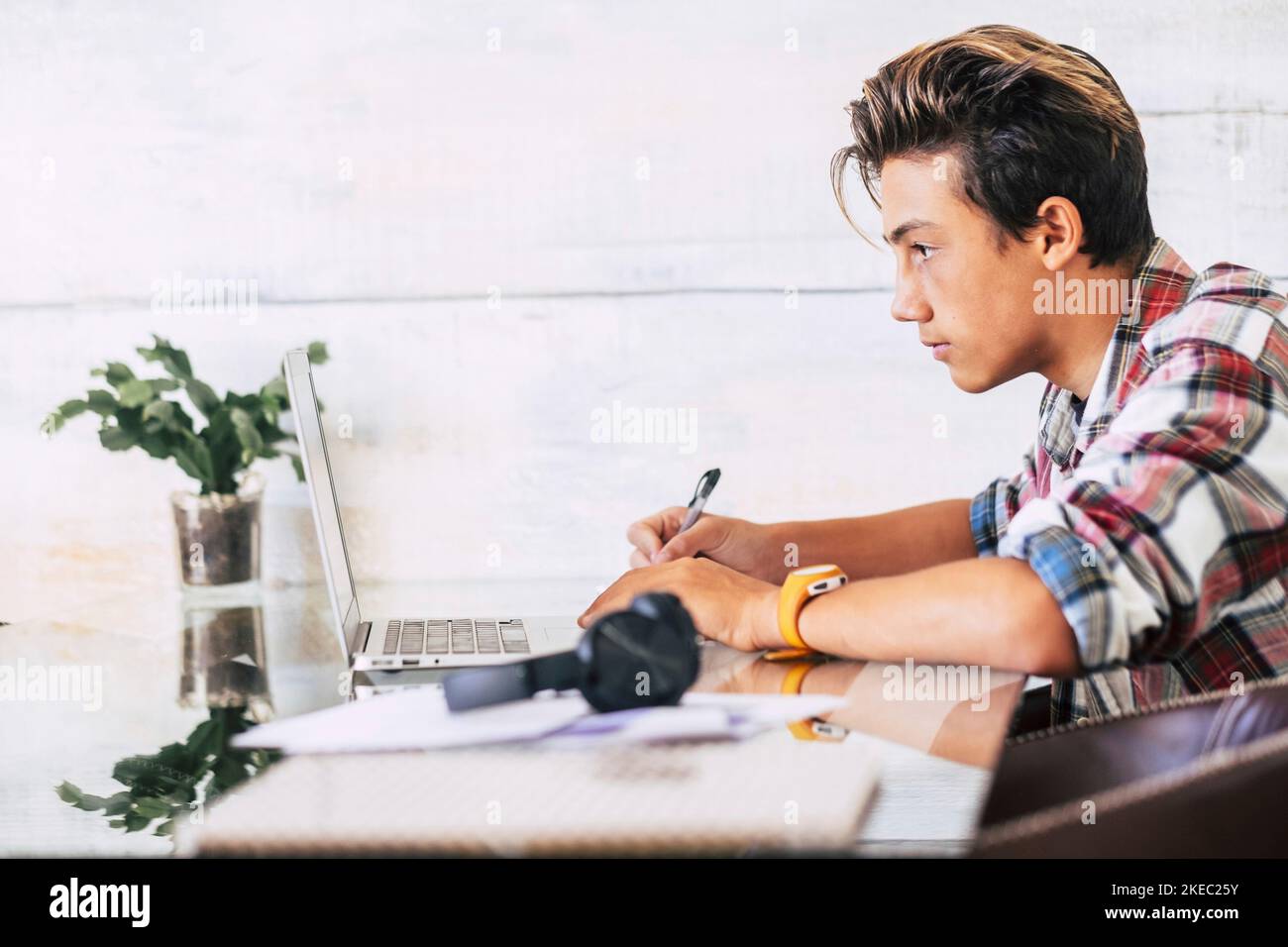 one young man or teenager studying and doing homework with laptop at ...